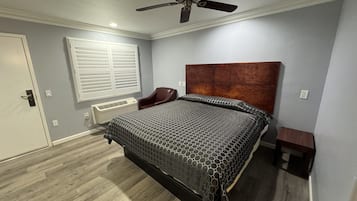 Quarto com cama, ventilador de teto, janela com persianas, radiador e porta.