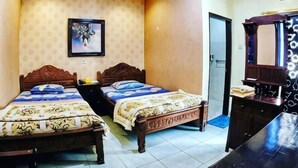 Quarto de hotel com duas camas, uma cômoda de madeira, um espelho e um quadro na parede.