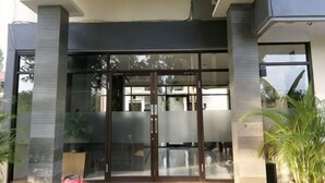 Entrada de um edifício com porta de vidro e um pilar de concreto.