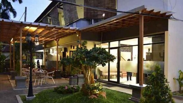 Um edifício moderno com área de estar coberta ao ar livre, uma janela grande e um jardim bem cuidado.