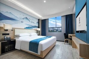 Quarto de hotel moderno com uma cama grande, uma escrivaninha, televisão e um mural na parede.