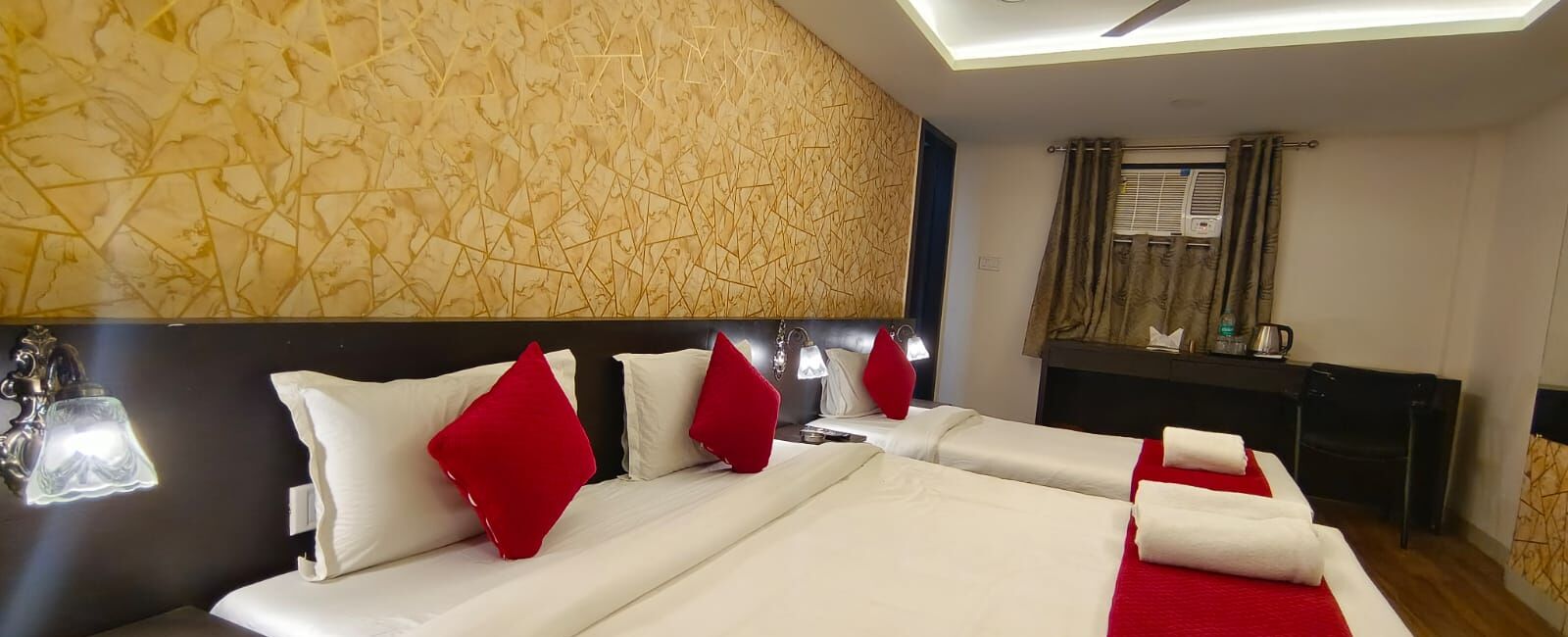 Quarto de hotel com duas camas, uma escrivaninha e um espelho.