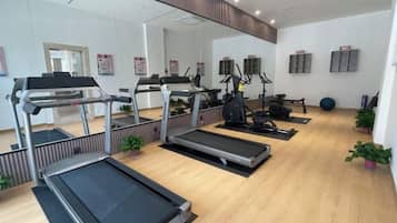 Uma academia com esteiras, bicicletas ergométricas e bolas de exercício.