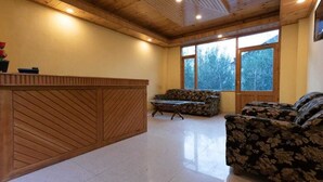 Um quarto espaçoso com um balcão de atendimento em madeira, um sofá e uma janela com vista para árvores.