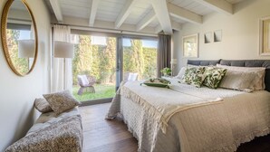 Quarto com uma cama grande, um espaço de estar com um banco e vista para o exterior.