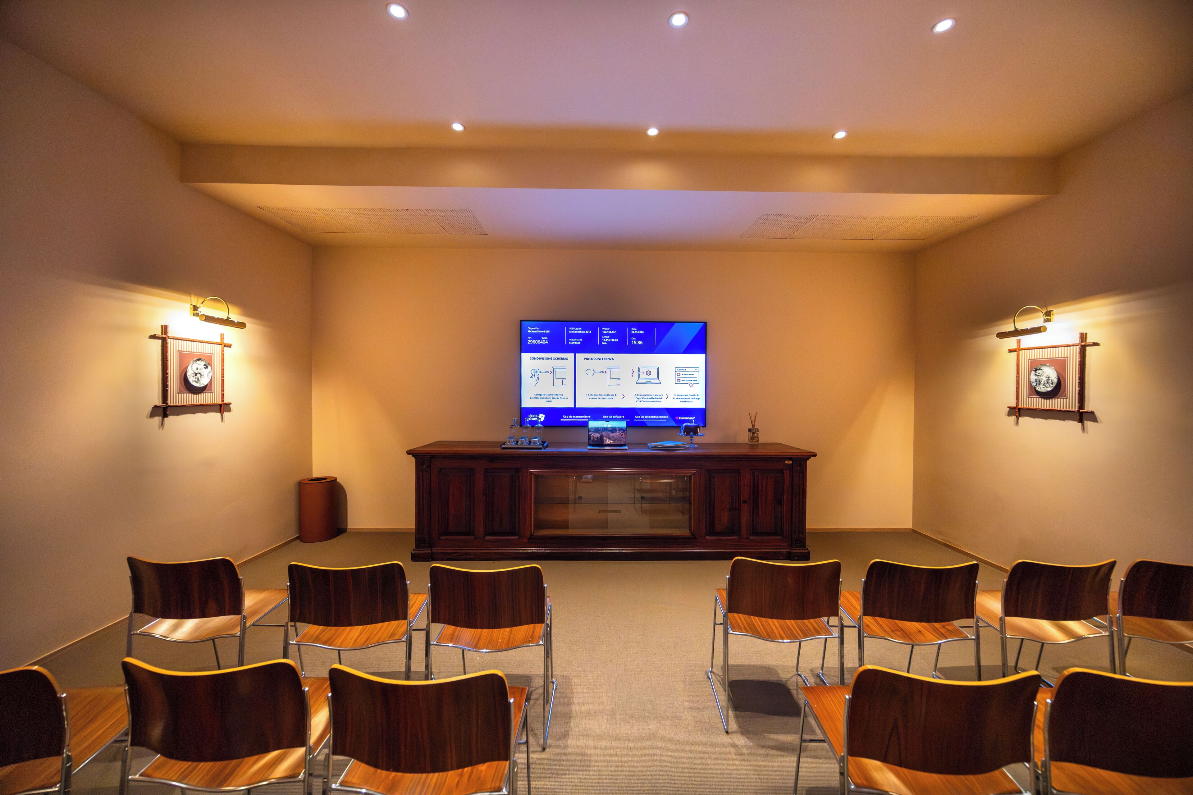 Uma sala de conferências com uma tela grande, cadeiras de madeira e um pódio.