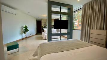 Quarto de hotel moderno com uma cama grande, televisão, secretária e vista para o exterior.