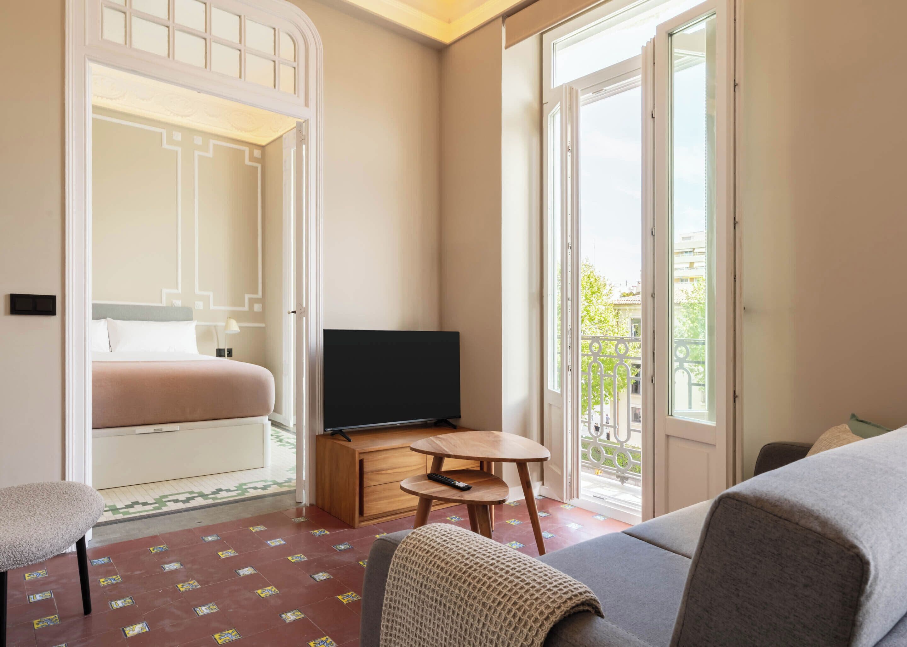 Quarto de hotel com cama, televisão, sofá e varanda com vista.