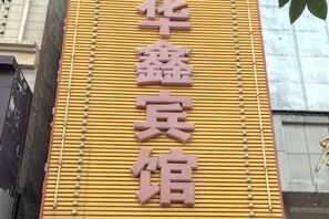 Fachada de edifício com parede amarela e um letreiro vertical com caracteres chineses.