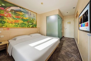 Quarto de hotel com uma cama, um quadro, uma televisão e uma porta.