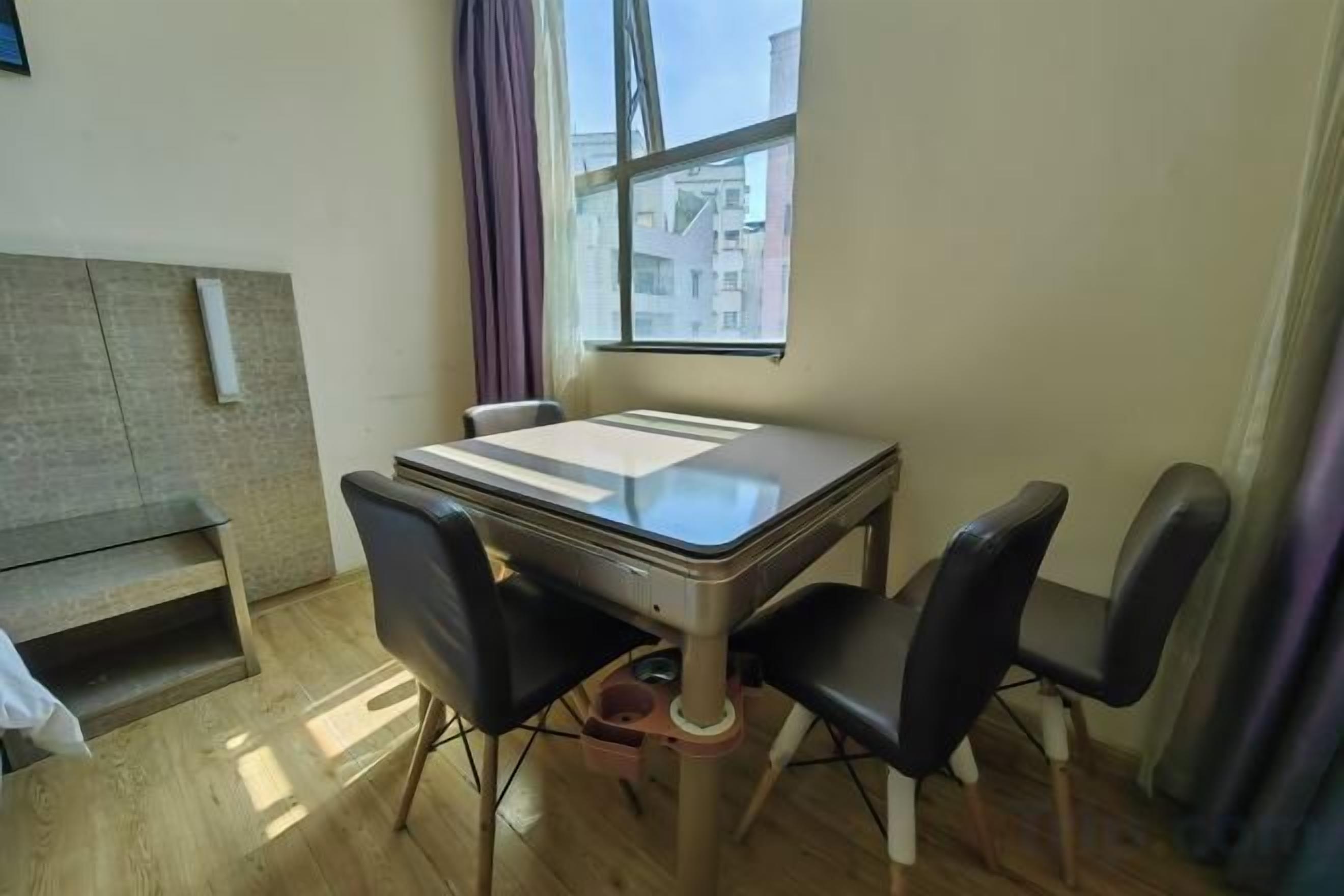 Uma área de refeições com mesa, cadeiras, um banco e uma janela com cortinas.
