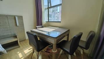 Uma área de refeições com mesa, cadeiras, um banco e uma janela com cortinas.