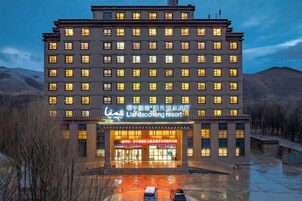 Um hotel com vários andares, entrada destacada e sinalização iluminada.