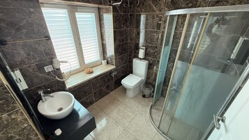 Uma casa de banho moderna com sanita, lavatório e chuveiro.