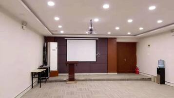 Uma sala de conferências com quadro branco, um palanque e um projetor.