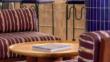 Área de estar com almofadas listradas e uma mesa redonda de madeira com um livro.