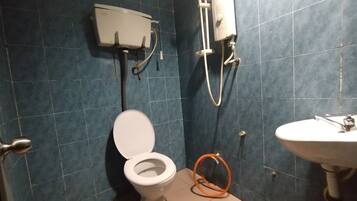 Casa de banho com sanita, chuveiro e lavatório.