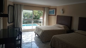 Quarto de hotel com duas camas, uma mesa, uma cadeira, uma televisão, um quadro e vista para uma piscina.