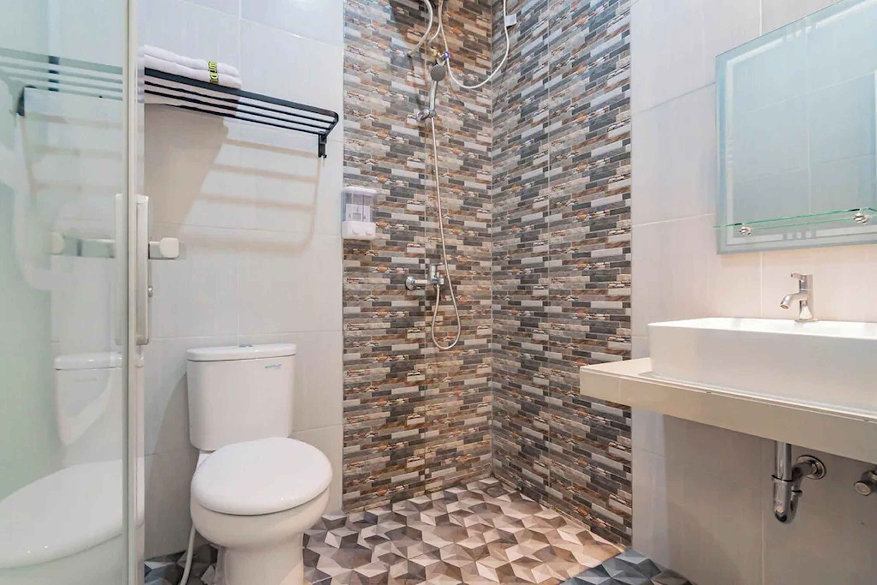 Uma casa de banho moderna com chuveiro, sanita e lavatório.