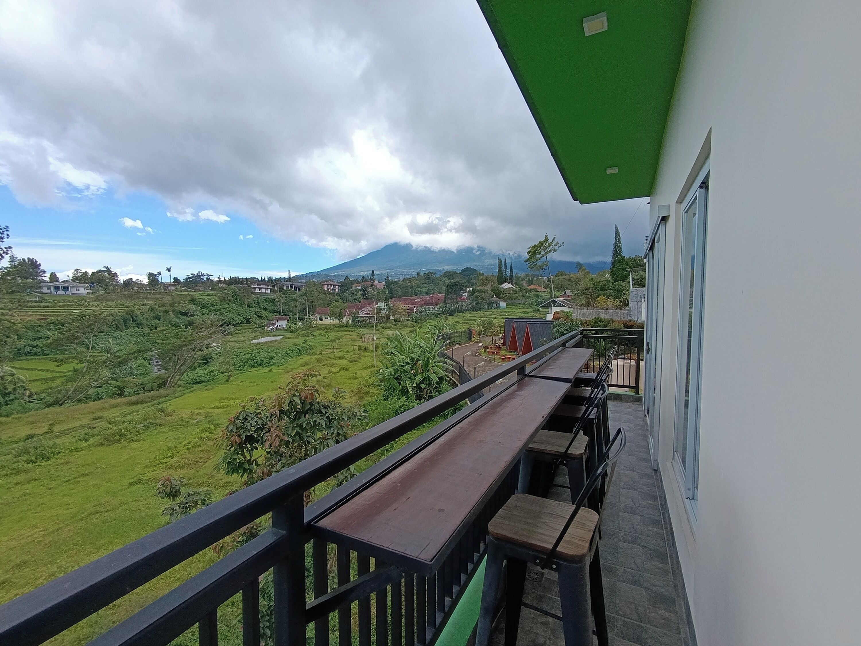 Uma varanda com vista para uma paisagem verde e uma montanha ao longe.