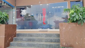 Entrada de hotel com fachada de vidro, escadaria e placa indicando wi-fi gratuito e serviços de segurança.