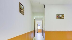 Um corredor com paredes brancas e laranja, duas portas e uma luminária no teto.