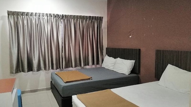 Quarto de hotel com duas camas, uma mesa e uma janela com cortinas.