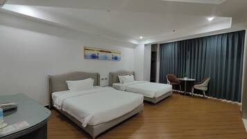 Quarto de hotel com duas camas, uma mesinha com cadeiras e um quadro na parede.