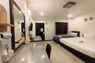 Quarto de hotel com cama, escrivaninha, secador de cabelo, espelho e porta.