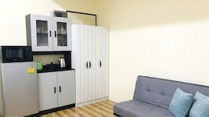 Um espaço compacto com cozinha compacta, sofá cinza e piso de madeira.