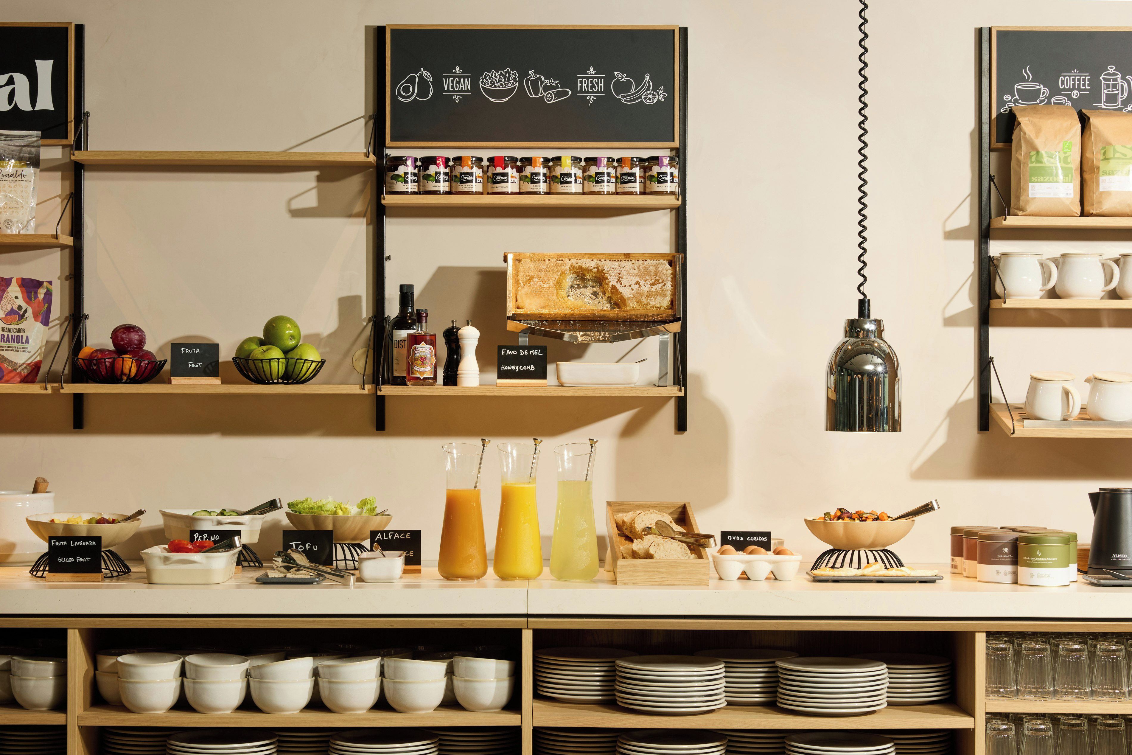 Interior de café com prateleiras cheias de potes, uma exposição de favos de mel e diversas opções de comida.