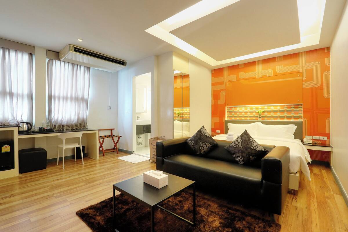 Quarto de hotel moderno com cama, sofá, escrivaninha e mesa de centro.