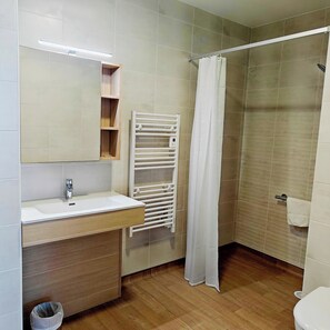 Casa de banho com lavatório, espelho, porta-toalhas, cortina de chuveiro e sanita.