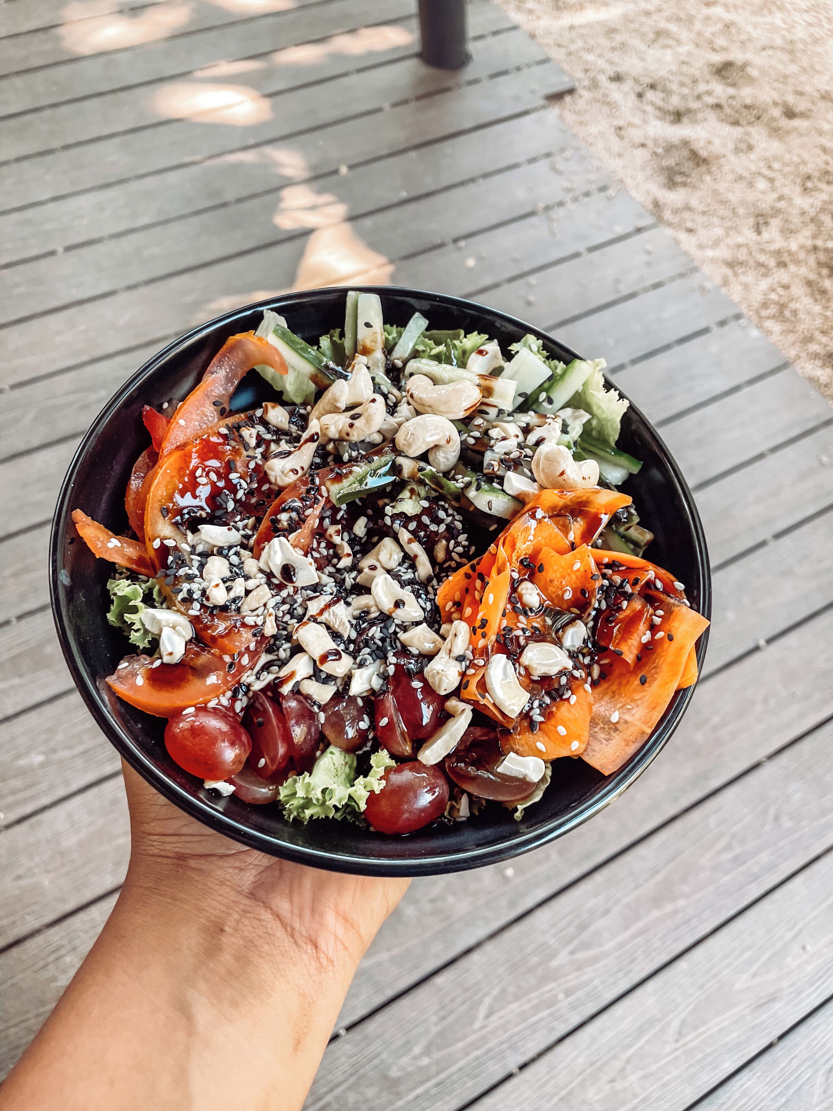 Uma pessoa segurando uma saladeira com vegetais e nozes variadas.
