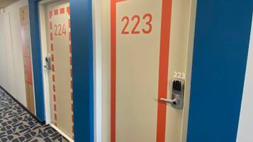 Fileira de quartos de hotel com portas numeradas 223 e 224, design moderno com detalhes em azul e vermelho.