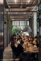 Restaurante com uma mesa grande compartilhada, rodeada por clientes.