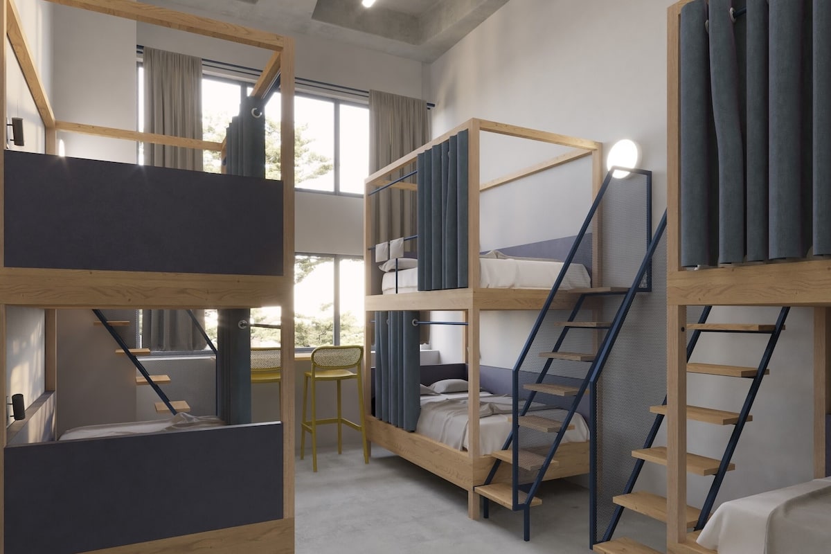 Um quarto de dormitório com beliches, uma escrivaninha e uma cadeira.