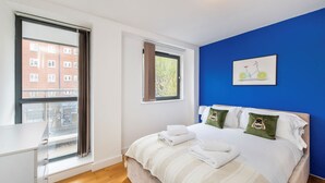 Quarto com cama, janela e parede azul.