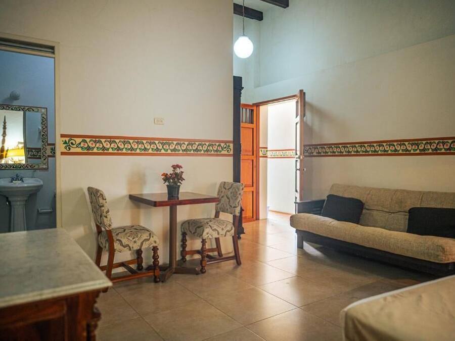 Uma sala de estar com sofá, duas poltronas, uma mesinha e um espelho.