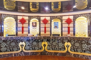 Uma área de recepção com balcão de mármore, detalhes decorativos vermelhos e quadros nas paredes.