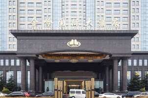 Entrada do Hotel Jinling International, com uma placa visível e uma van branca estacionada na frente.