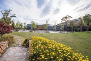 Um jardim bem cuidado com um caminho, área gramada e uma fileira de flores amarelas.