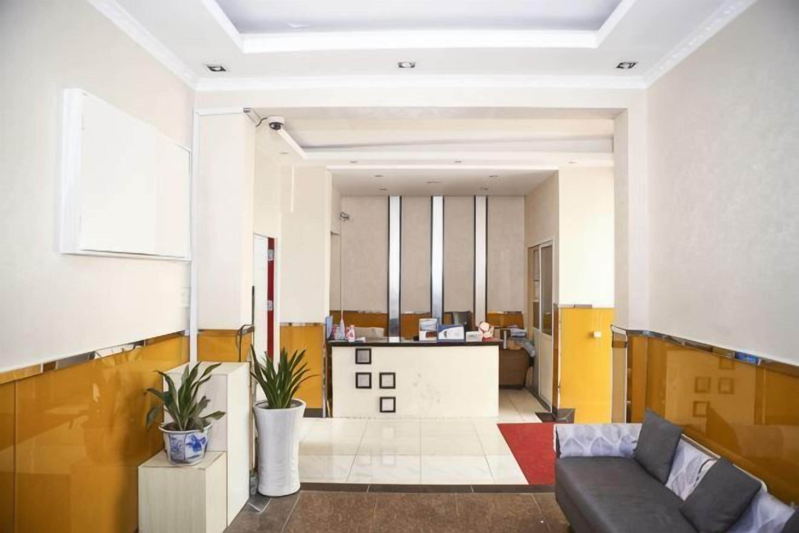 Um saguão de hotel com balcão de recepção, um sofá e um vaso de plantas.