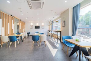 Decoração moderna com mesas e cadeiras dispostas para refeições, uma janela ampla com vista e teto com iluminação embutida.