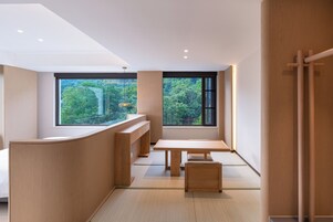 Um interior moderno com um balcão de atendimento de madeira, um banco e janelas amplas com vista para áreas verdes.