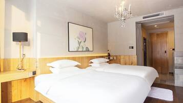 Quarto de hotel com uma cama grande, um abajur, um candelabro e um quadro na parede.