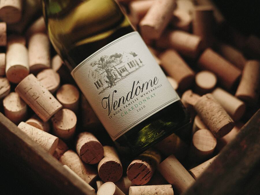 Uma garrafa de vinho com etiqueta, rodeada por várias rolhas.
