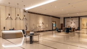 Um hall de hotel moderno com balcão de recepção, área de estar e arte decorativa na parede.