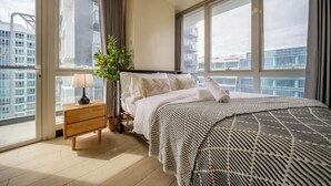 Quarto moderno com uma cama grande, mesa de cabeceira, luminária e um vaso com planta.