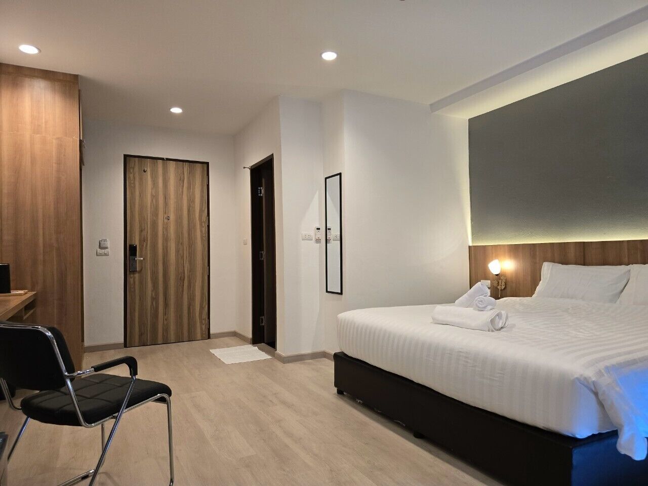 Quarto de hotel moderno com uma cama grande, uma mesa de trabalho e um guarda-roupa.